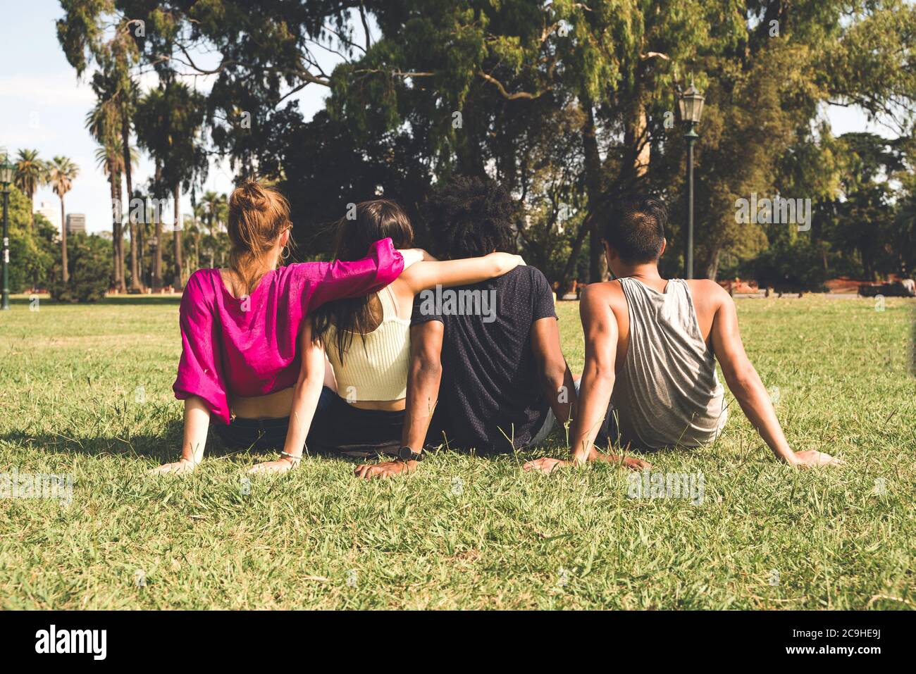 A group of friends sitting together in a park and enjoying a warm ...
