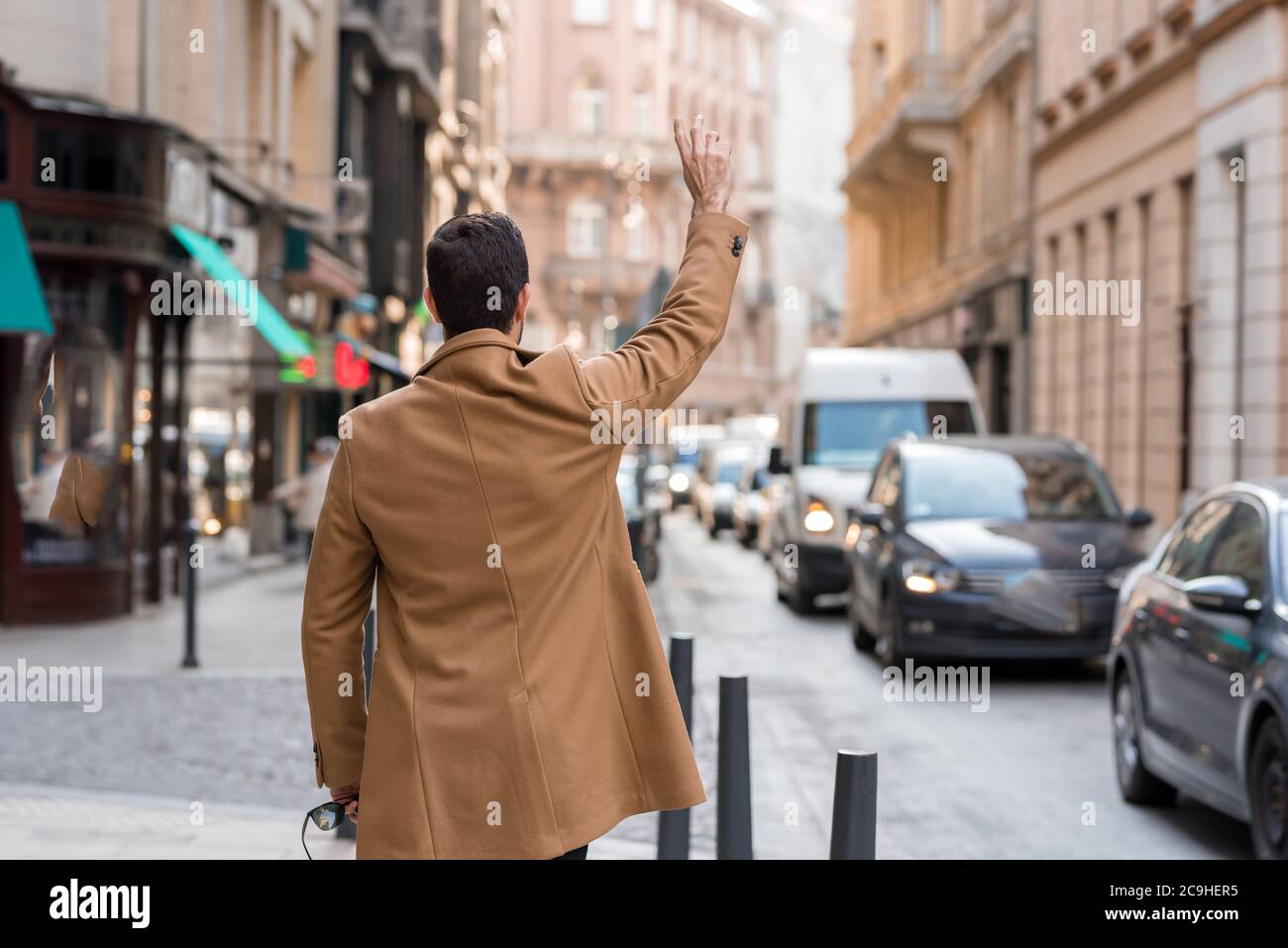 A handsome elegant man walking on the streets and waving with his hand ...