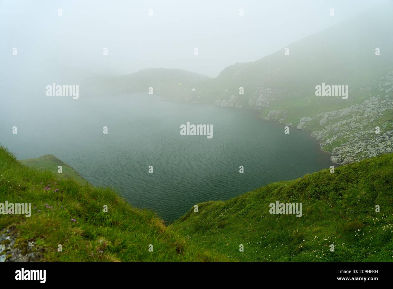 Landscape with a glacial lake in the mountains in the mist Stock Photo ...