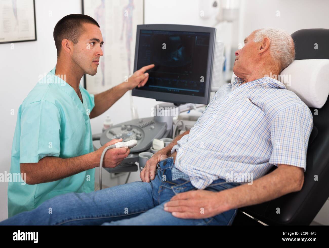Young male doctor using ultrasound scan doing abdominal diagnostic to ...