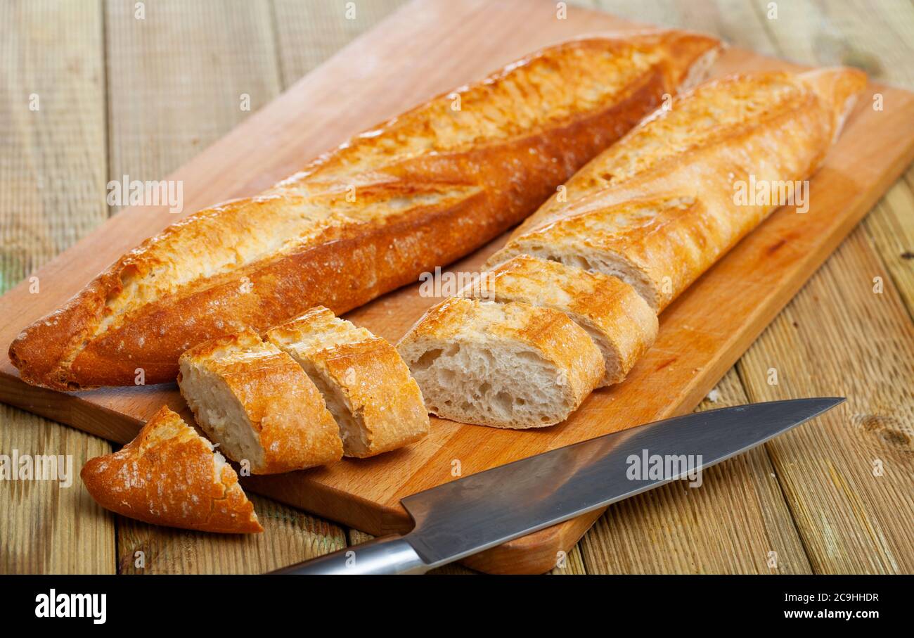Sliced freshly baked French baguette with appetizing crispy crust on ...