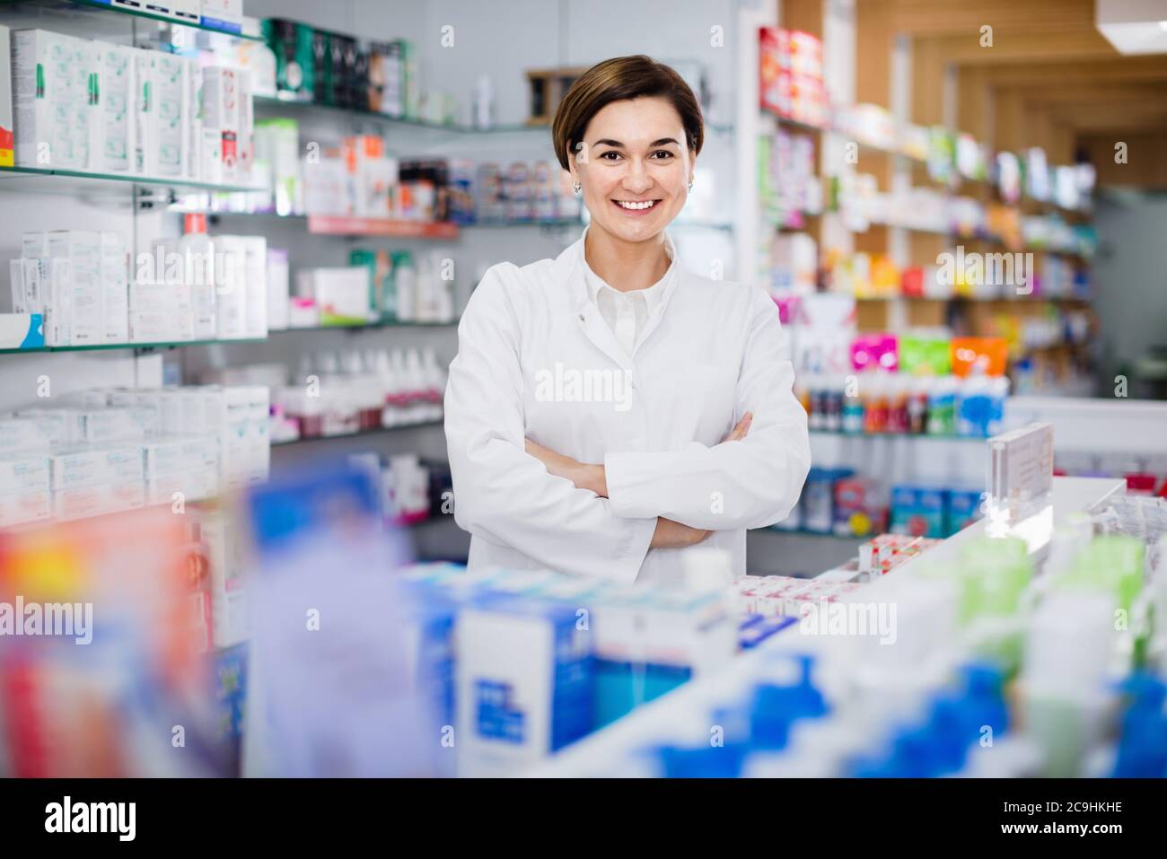 Diligent friendly smiling female pharmacist arranging displayed ...