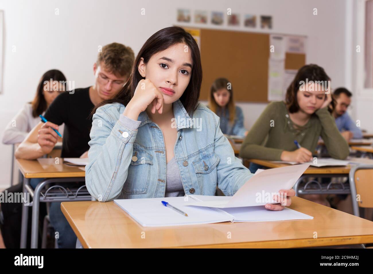 Smiling young schoolgirl is sitting test and answer about task in the ...