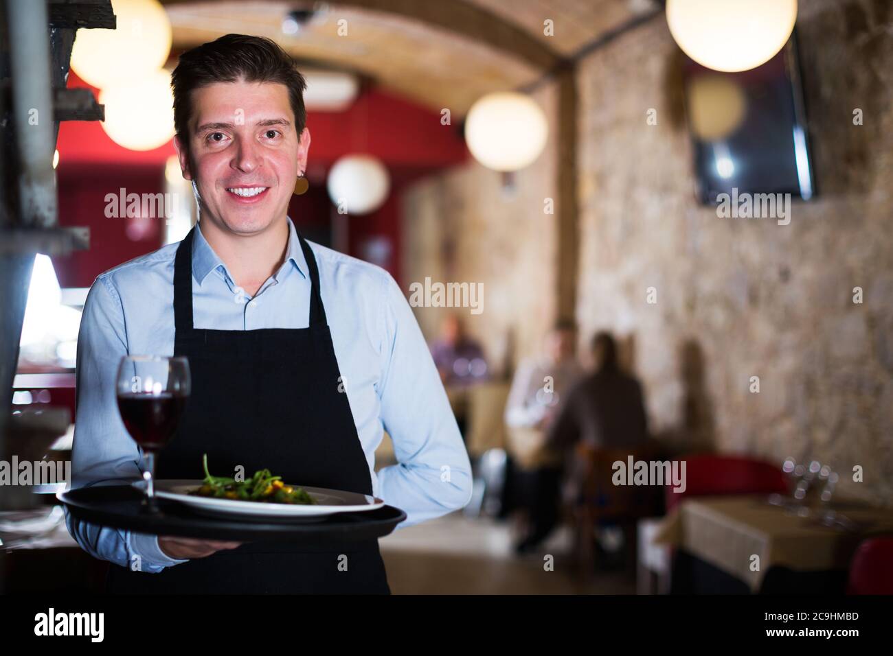 Handsome smiling waiter with serving tray welcoming to restaurant Stock ...