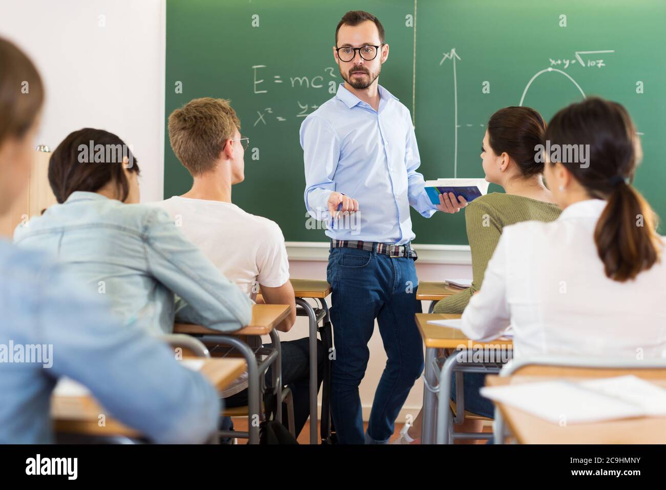 Teacher is giving lecture for students with book in the class Stock ...