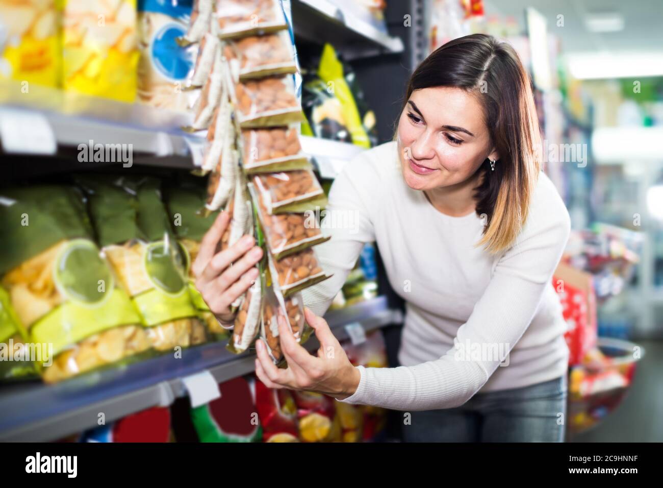 cheerful girl customer looking for tasty snacks from shelves in ...