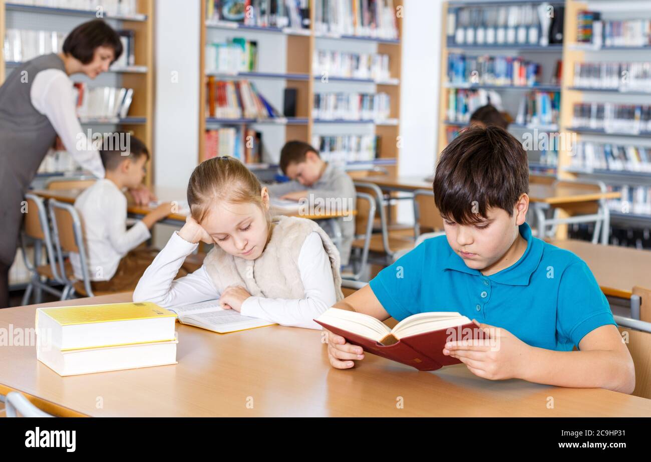 Cute tween girl and intelligent boy studying together in school library ...