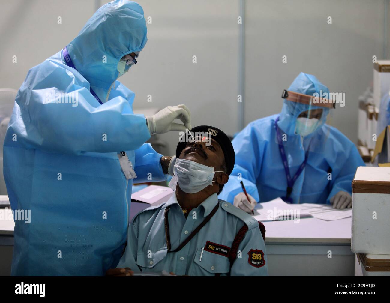 A health worker wearing Personal Protective Equipment (PPE) collects a ...