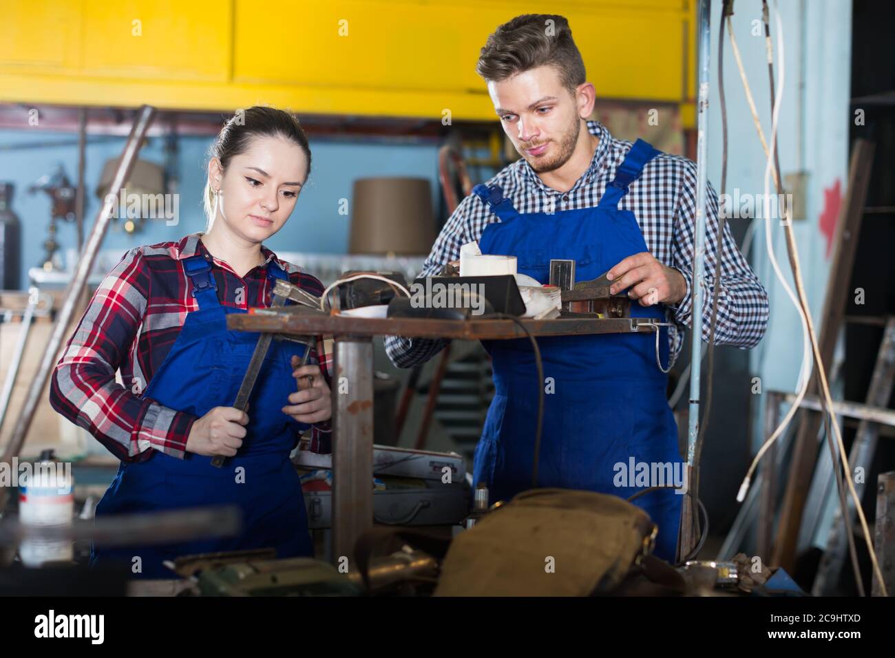 two masters are standing near table and working together in workshop ...