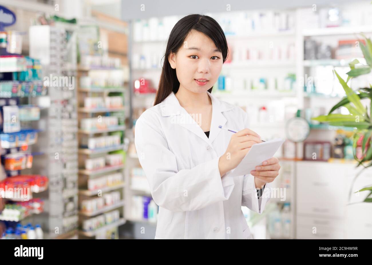Chinese female is checking medicine with notebook in pharmacy Stock ...
