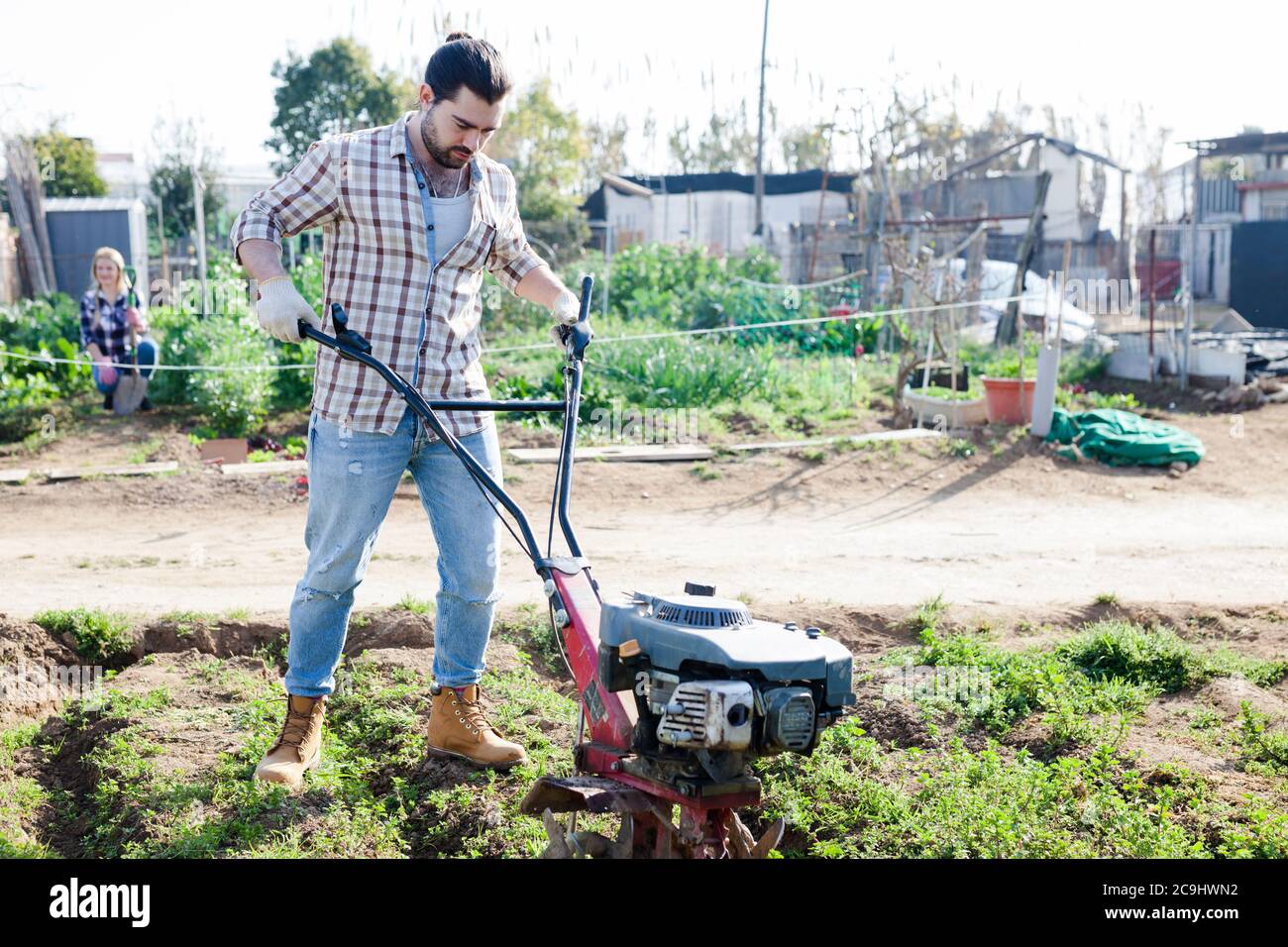 Man professional gardener using plow at land with green grass in garden ...