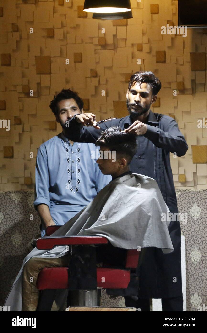 Rawalpindi, Pakistan. 31st July, 2020. A barber trims a customer's hair ...
