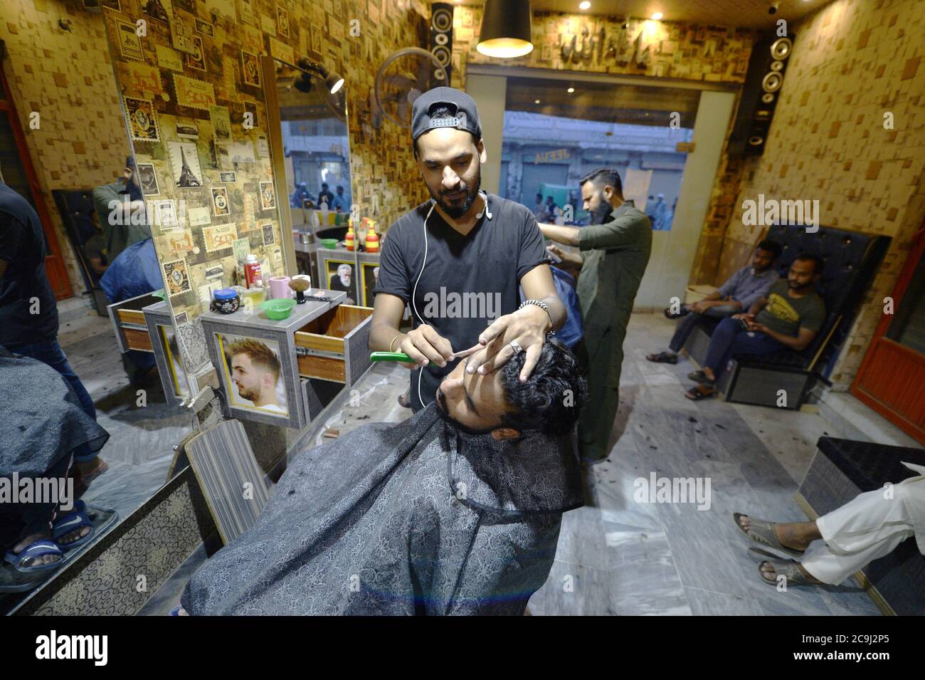 Rawalpindi, Pakistan. 31st July, 2020. A barber trims a customer's ...