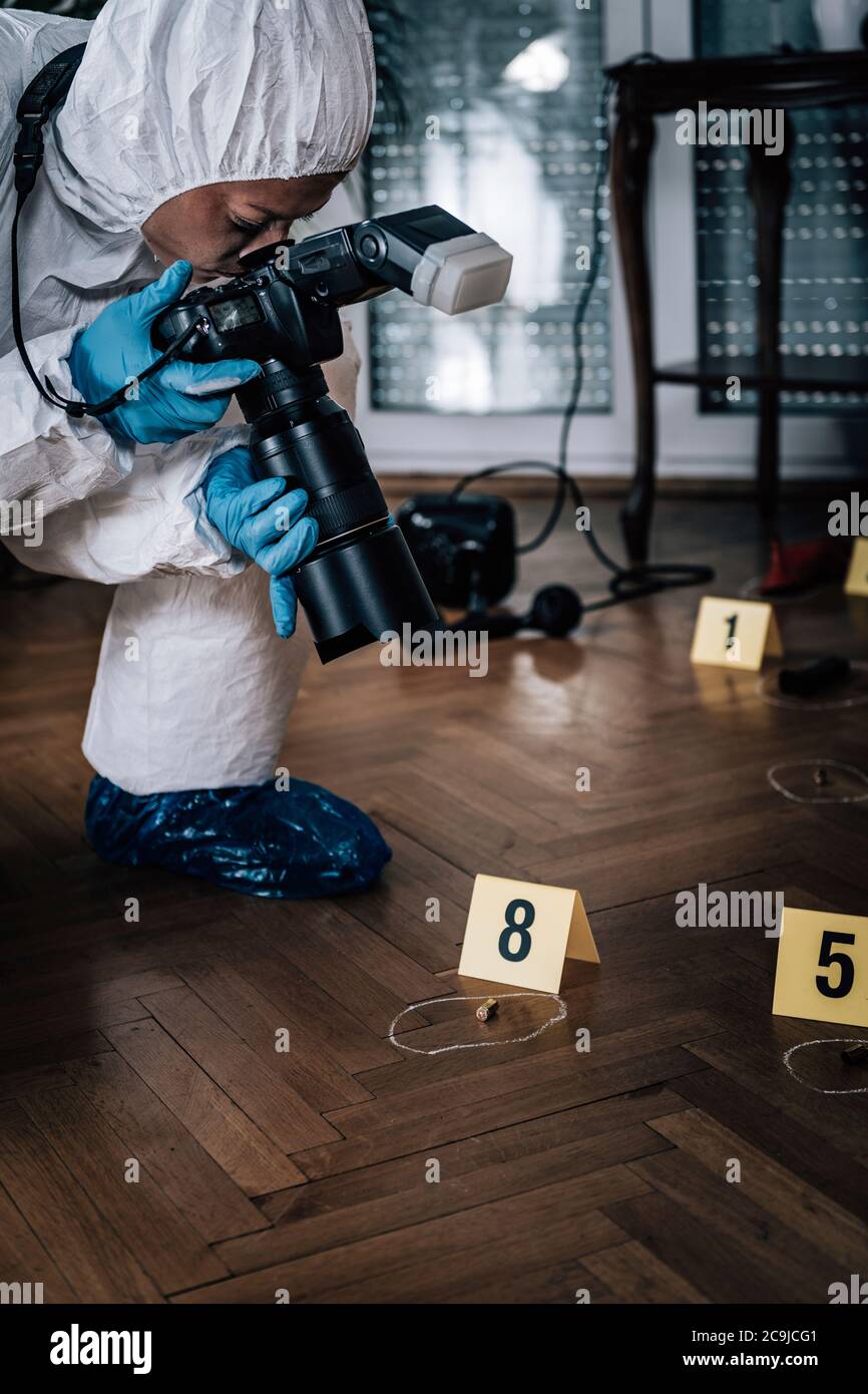 Crime scene. Forensics expert photographing evidence at a crime scene ...
