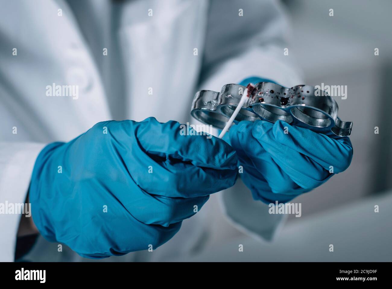 Forensic Science in Lab. Forensic Scientist examining a knuckle duster ...