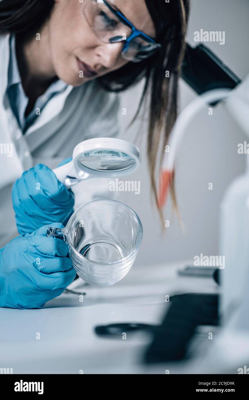 Forensic Science in Lab. Forensic Scientist examining glass for ...