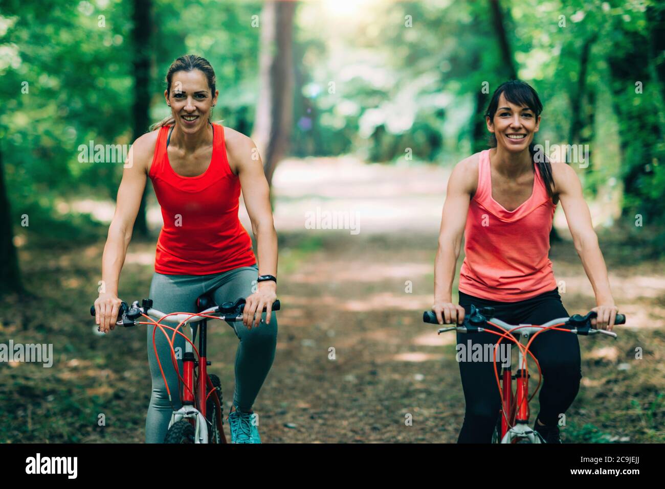 Female friends riding bikes together in park Stock Photo - Alamy