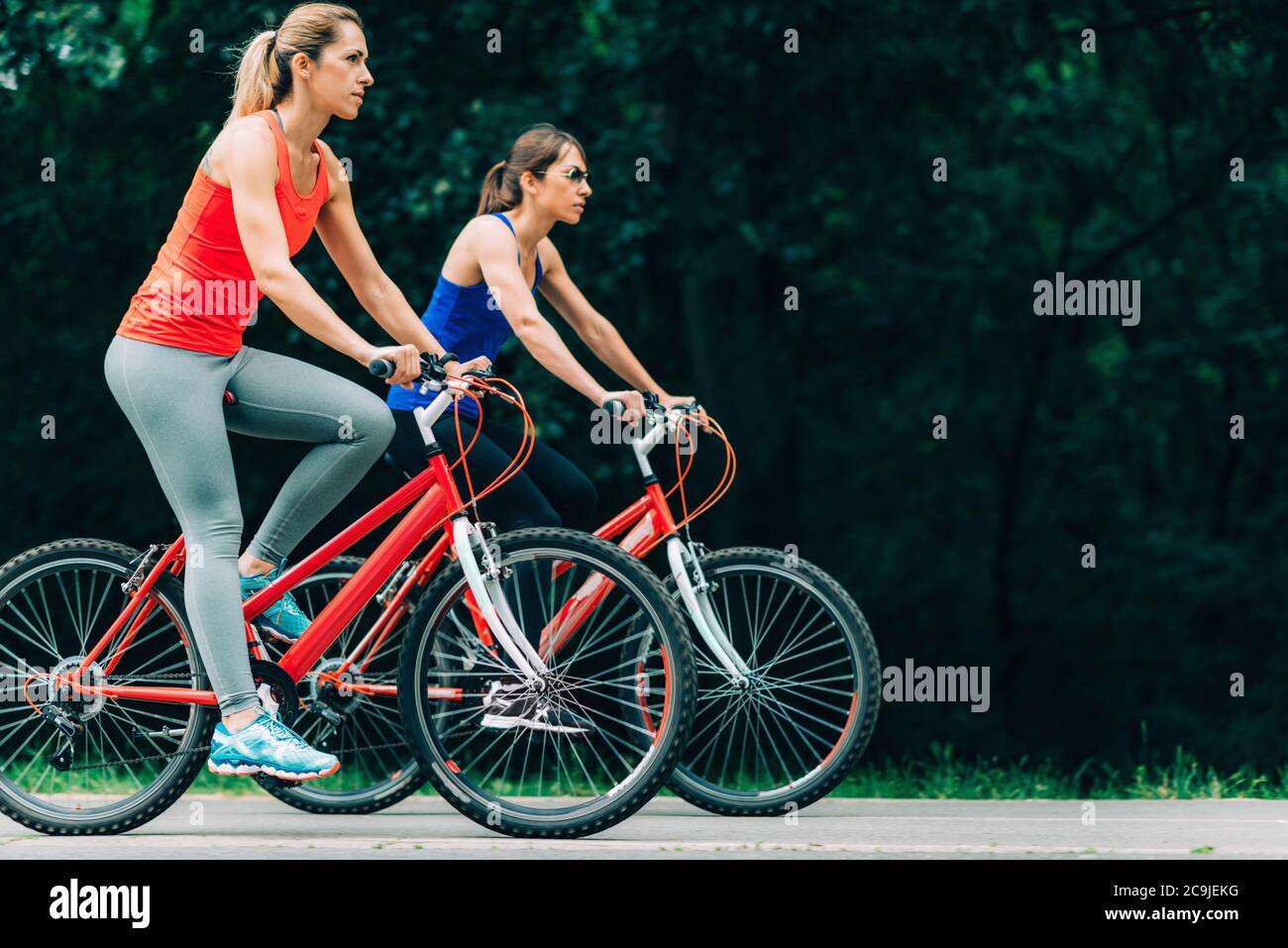 Female friends riding bikes together in park Stock Photo - Alamy