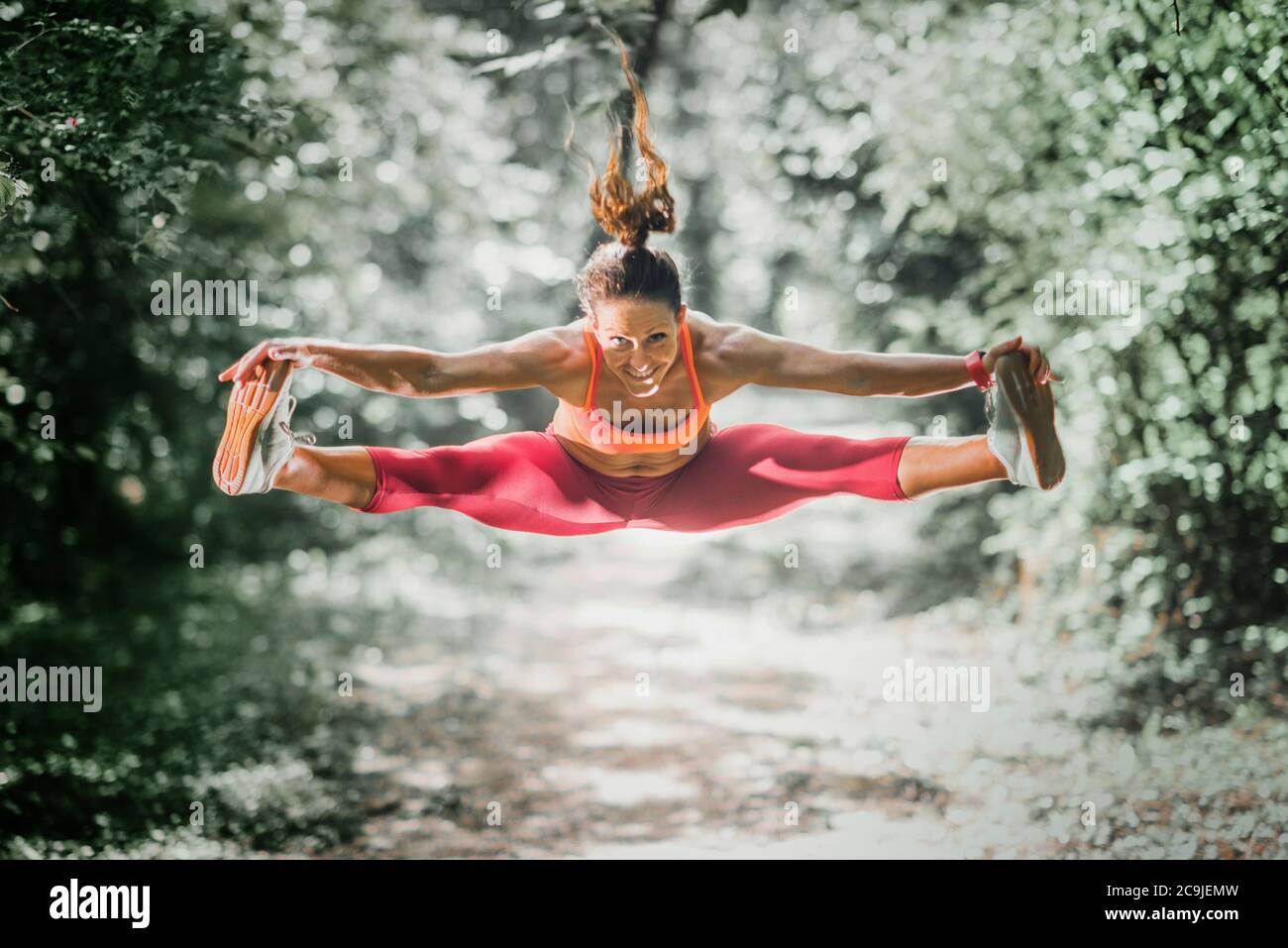 Female athlete jumping in a park Stock Photo - Alamy