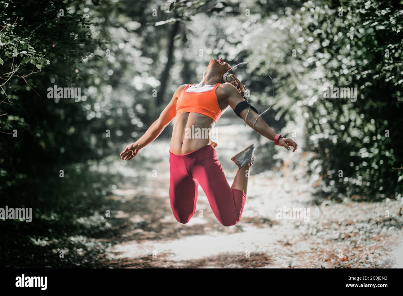 Female athlete jumping in a park Stock Photo - Alamy