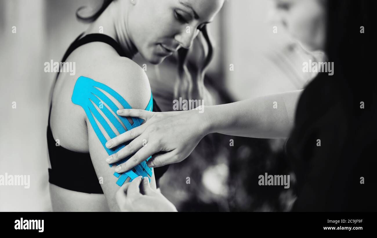 Physical therapist placing kinesio tape on patient's shoulder Stock Photo - Alamy