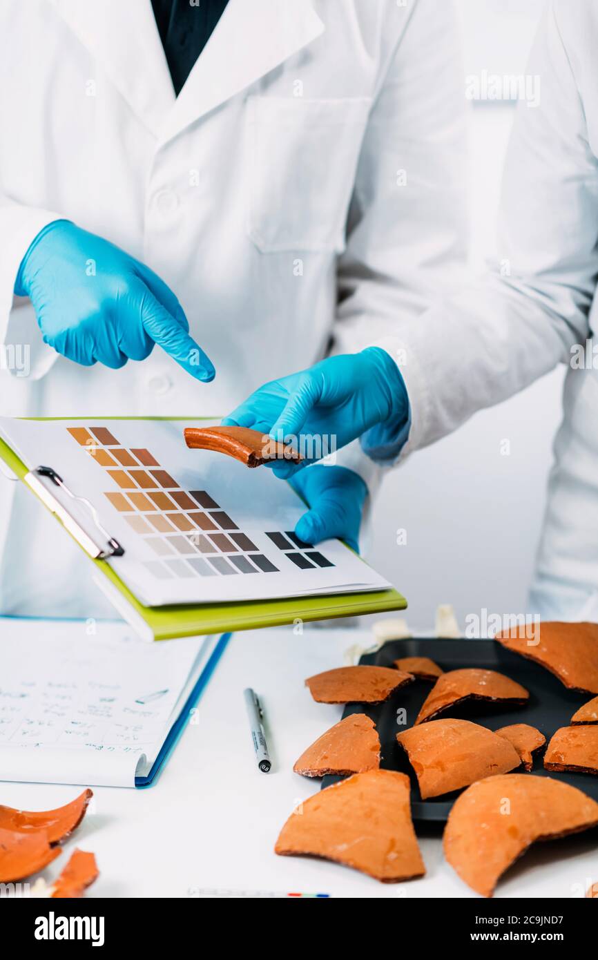Young archaeologist comparing pottery colours with colour chart scheme ...