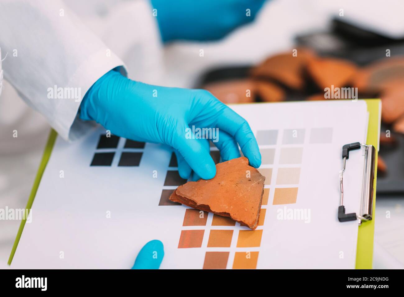 Young archaeologist comparing pottery colours with colour chart scheme ...