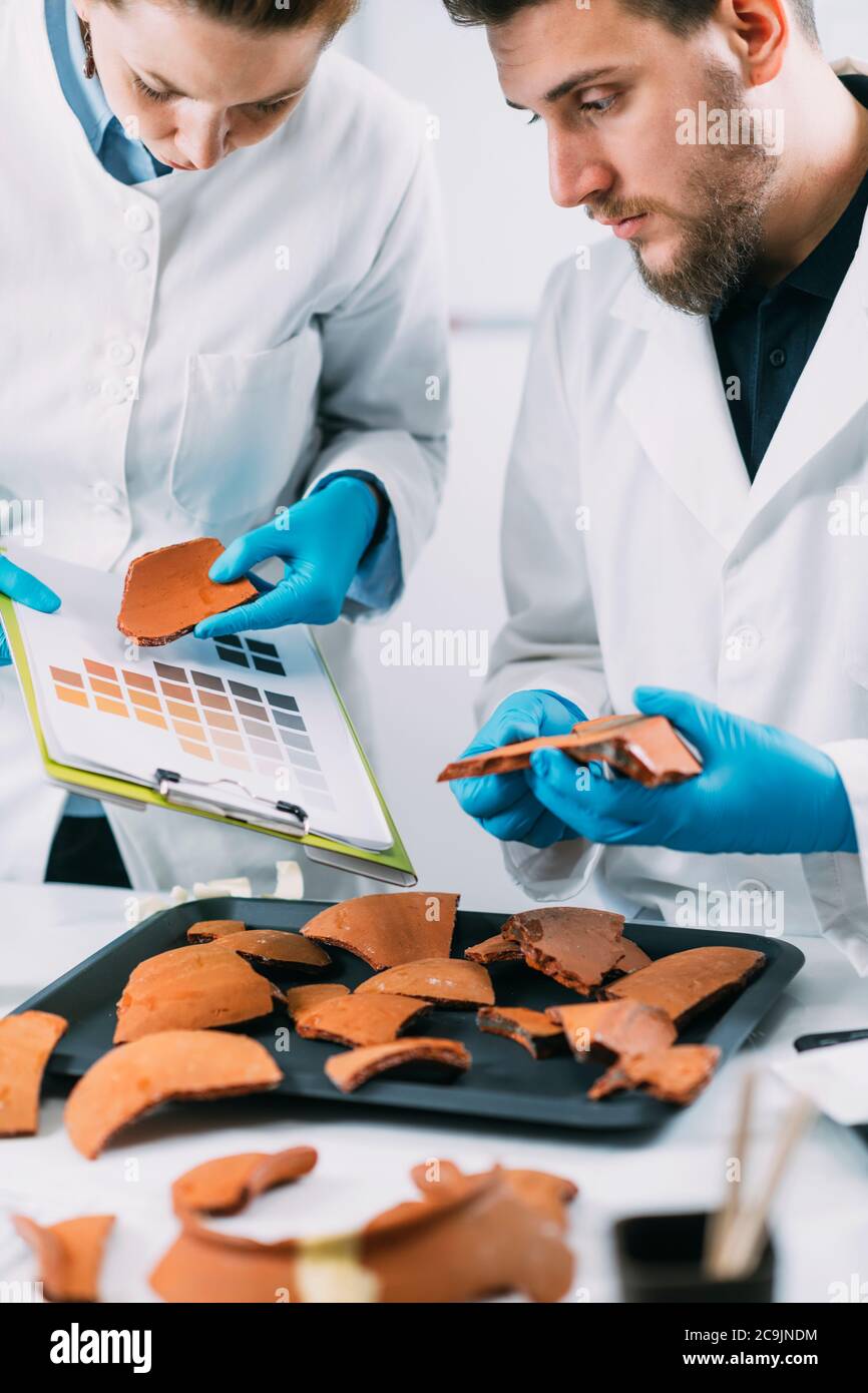 Young archaeologist comparing pottery colours with colour chart scheme ...