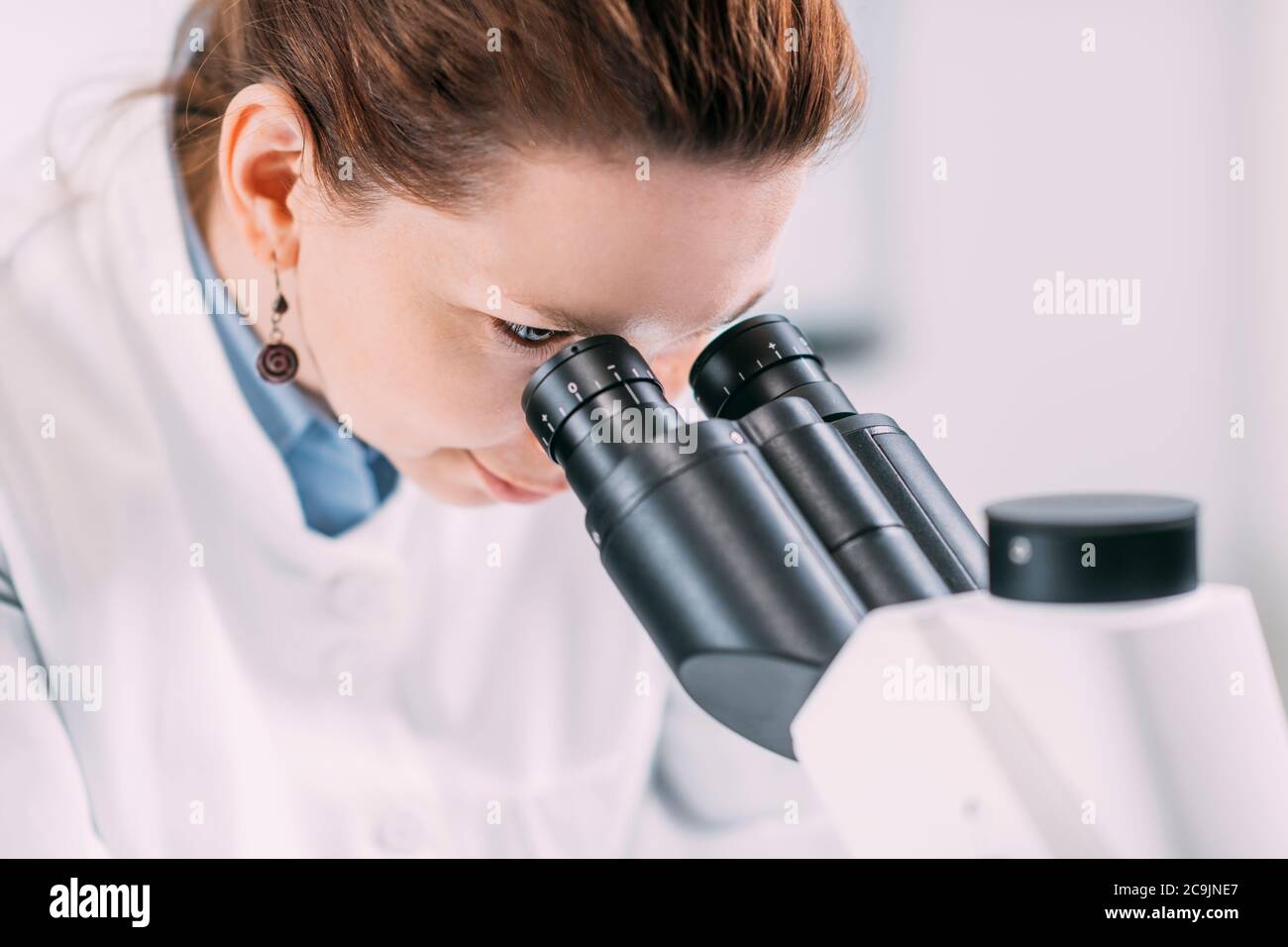 Portrait of young female archaeologist with microscope in laboratory ...