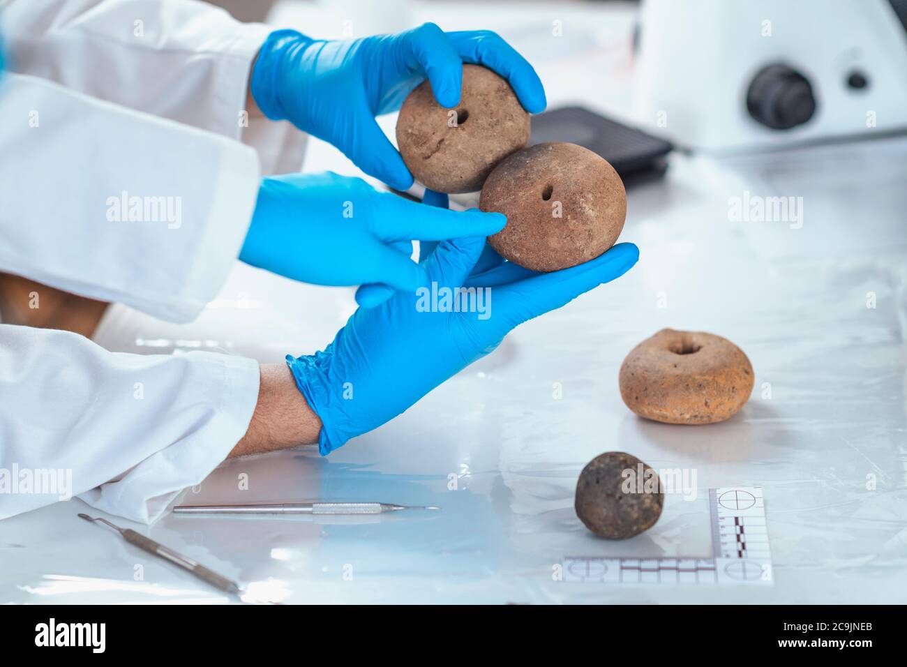 Archaeologist analyzing ancient artefacts, loom weight or fishing net ...