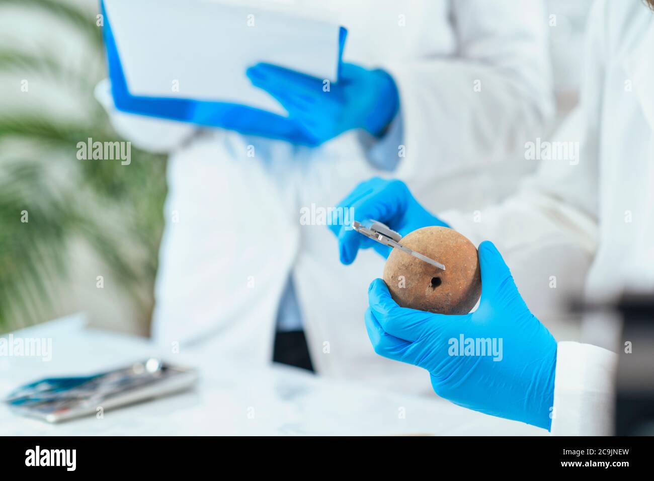 Young male archaeologist measuring ancient artefacts in laboratory ...