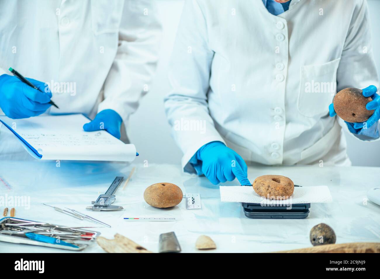 Archaeologist measuring ancient artefact loom weight or weight for ...