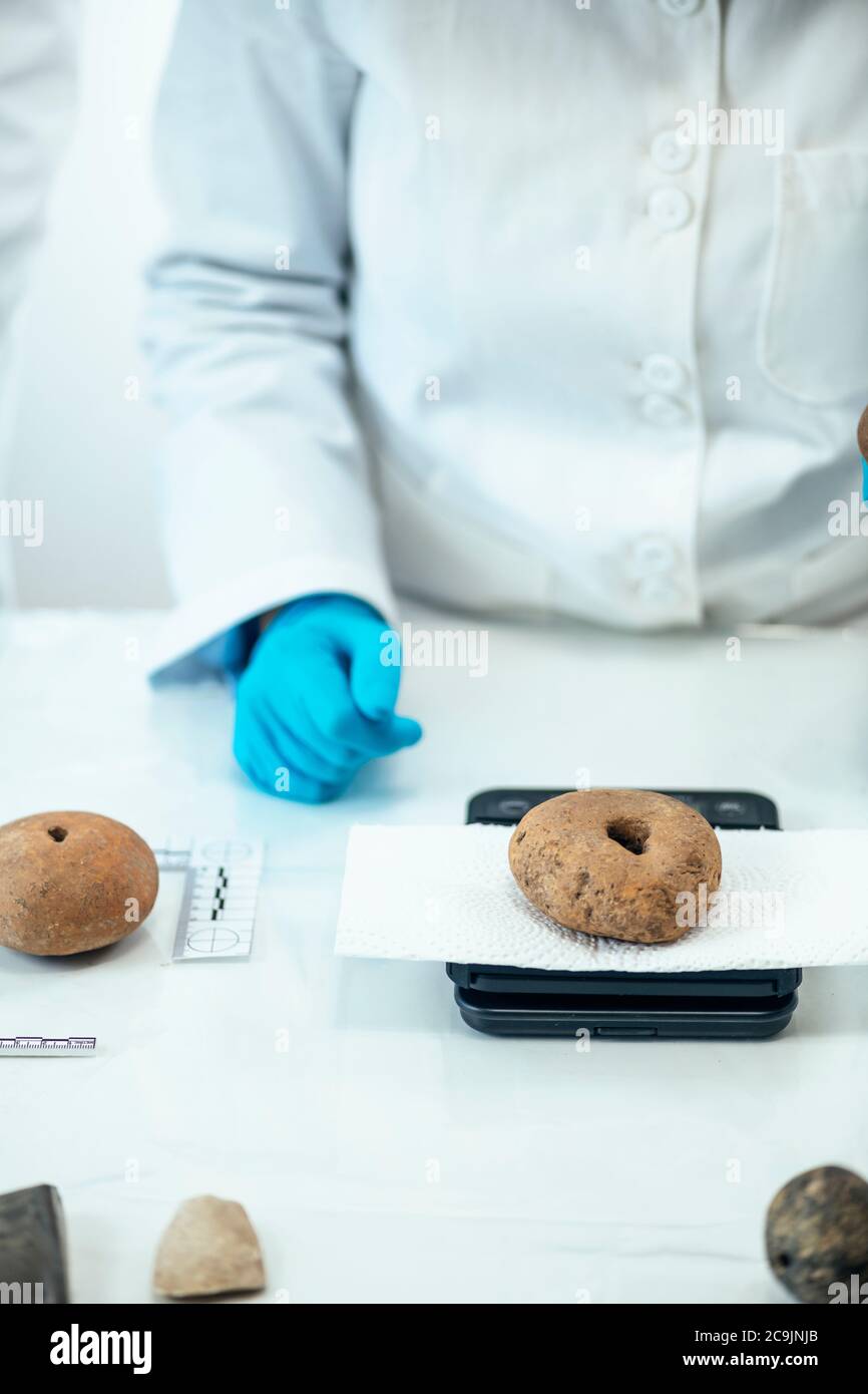 Archaeologist measuring ancient artefact loom weight or weight for ...