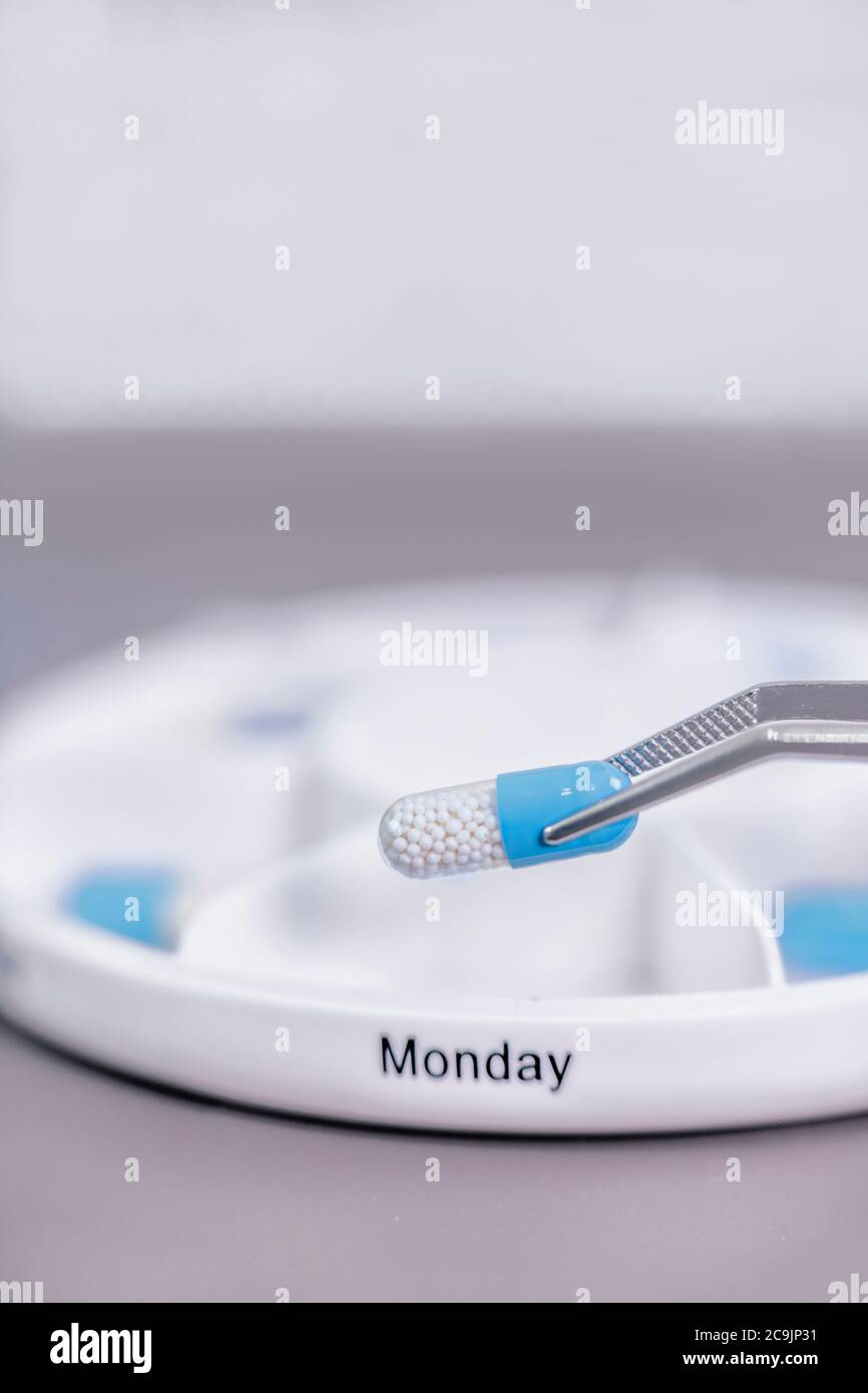 Sorting medications. Hands sorting medication with tweezers into 7 day ...