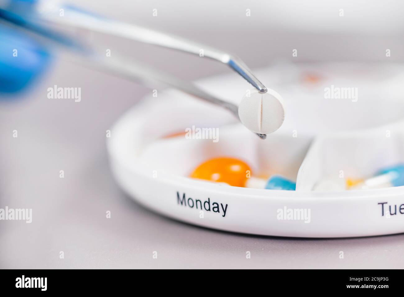 Sorting medications. Hands sorting medication with tweezers into 7 day ...