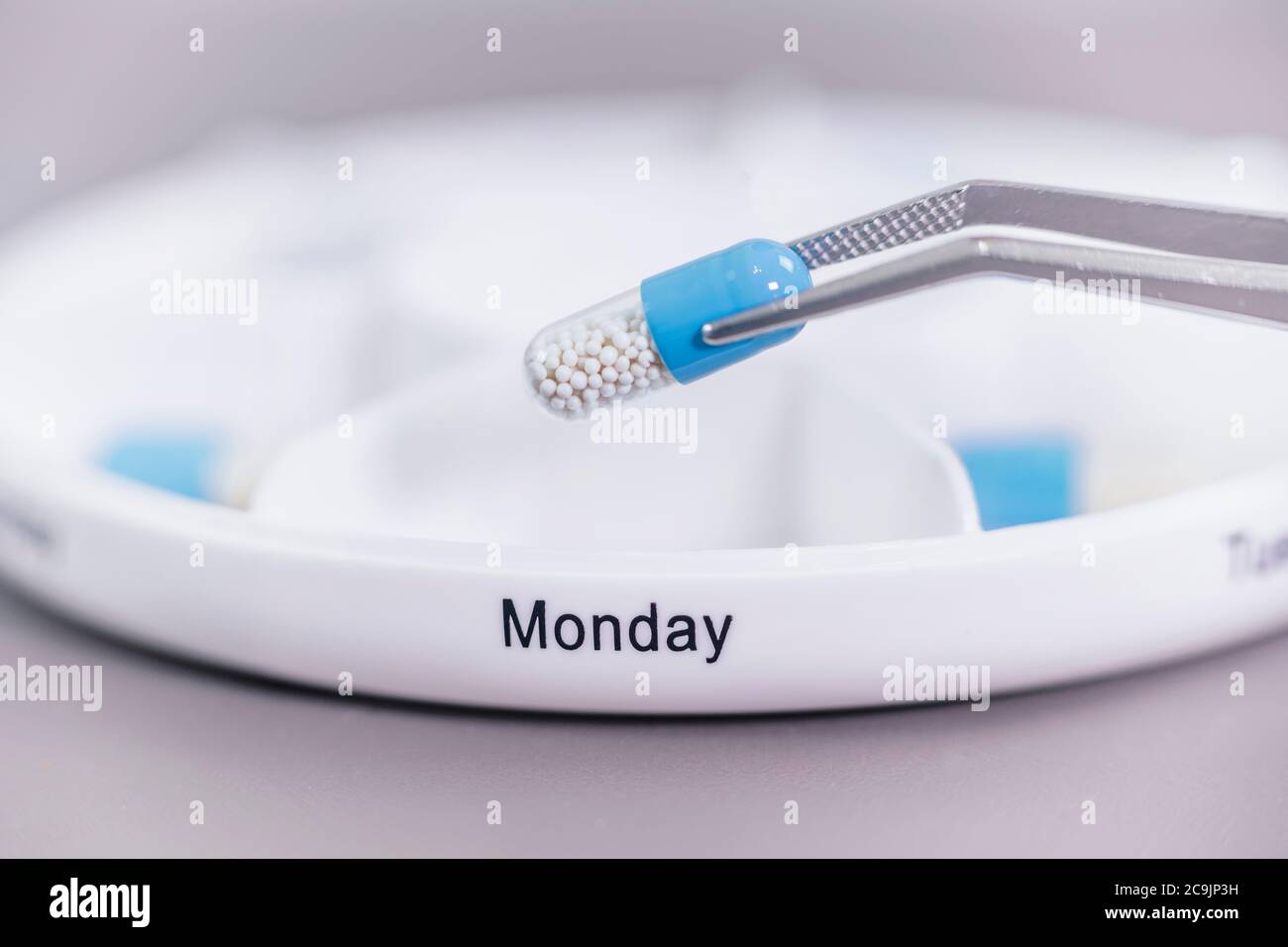 Sorting medications. Hands sorting medication with tweezers into 7 day ...