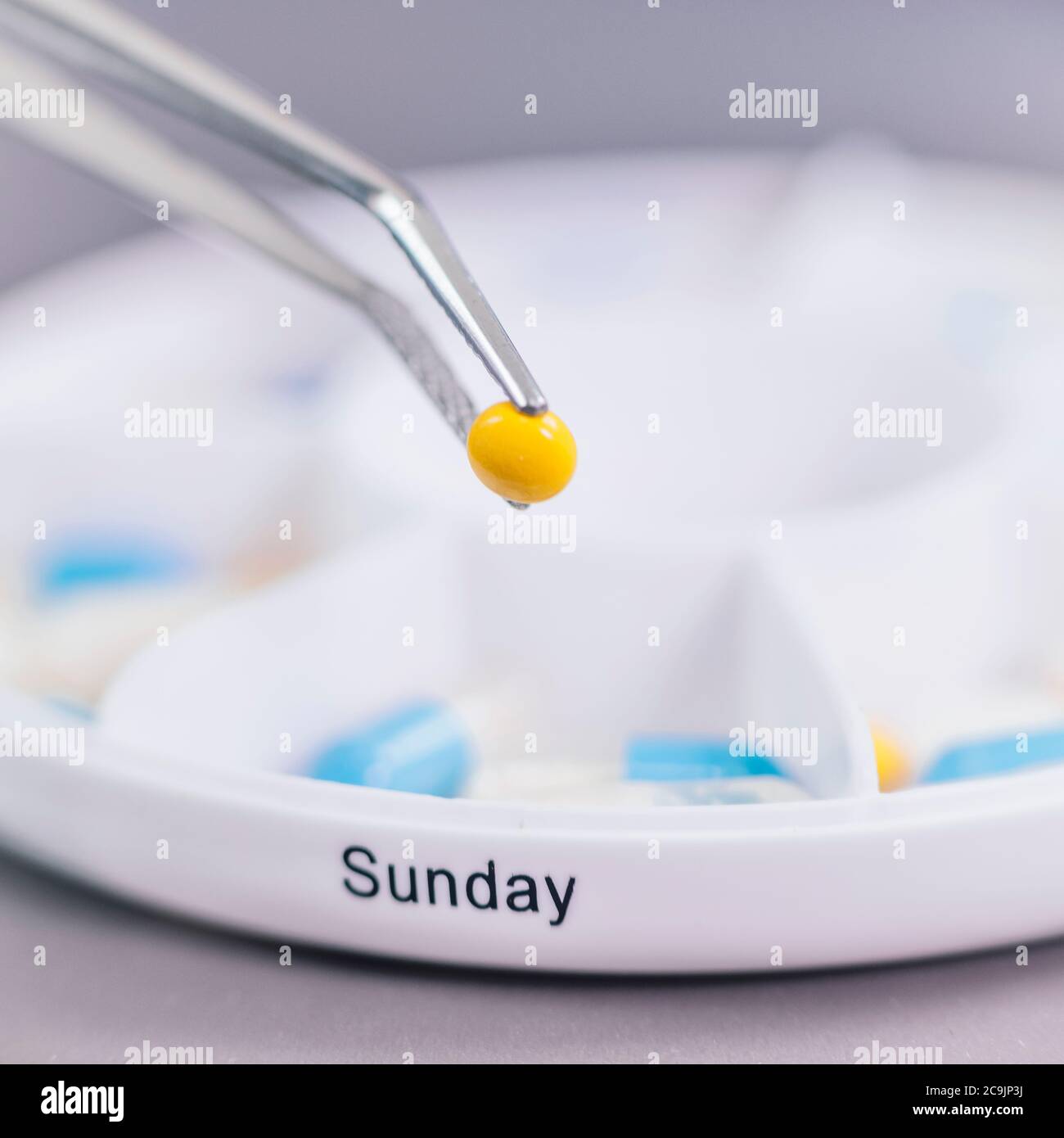 Sorting medications. Hands sorting medication with tweezers into 7 day ...