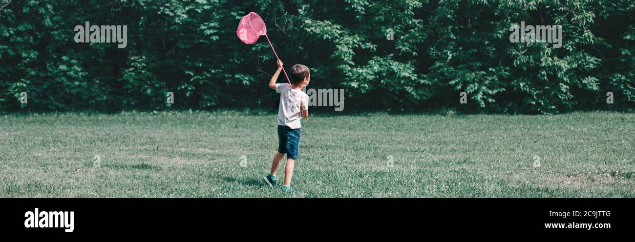 Boy with pink butterfly net walking alone park. Child playing catching ...