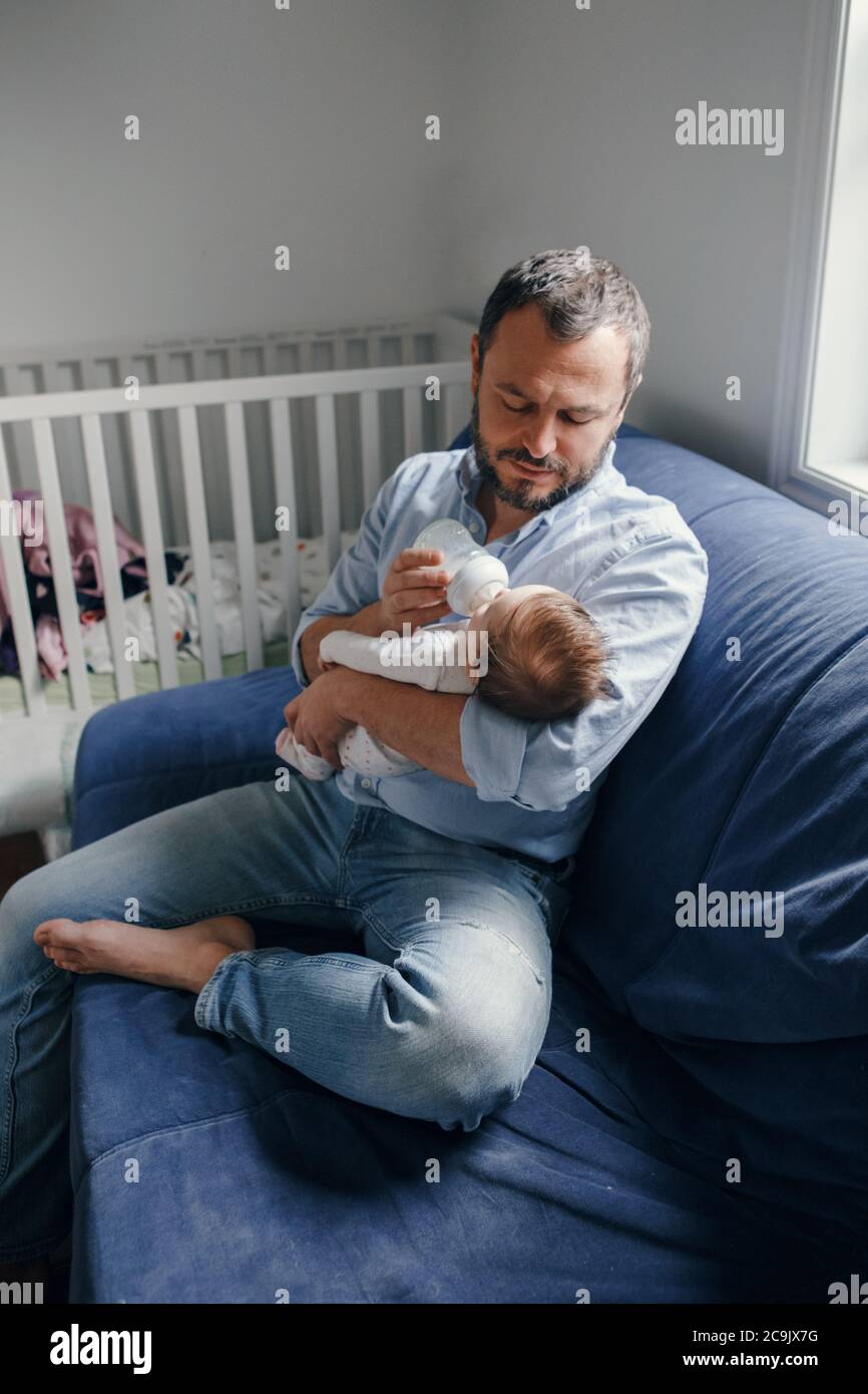 Middle age Caucasian father feeding newborn baby from bottle milk. Man ...