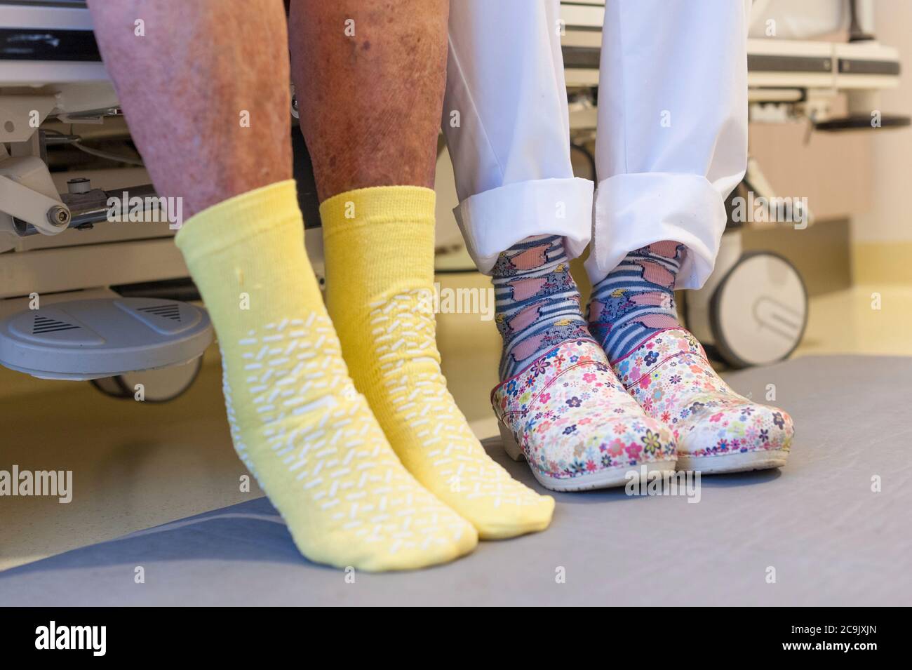 Geriatric hospital ward. Close-up of a nurse (right) wearing clogs and ...