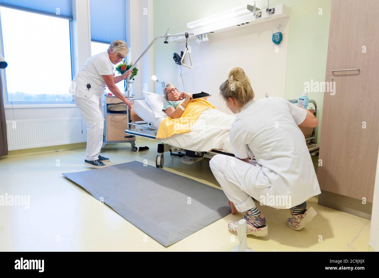 Geriatric hospital ward. Nurses helping a confused patient on the ...