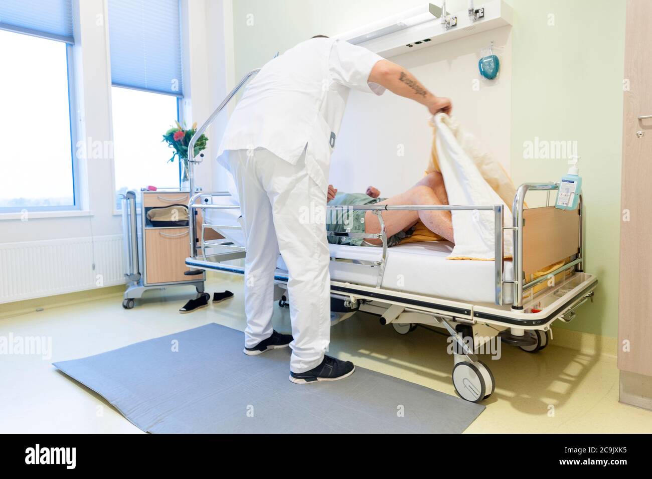 Geriatric hospital ward. Nurse helping a confused patient on the ...