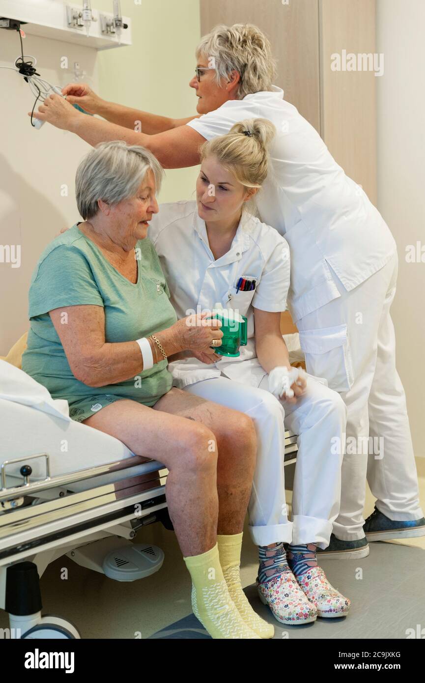 Geriatric hospital ward. Nurses helping a confused patient on the ...