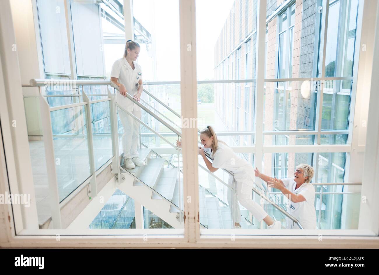 Nurses laughing and sliding down the stairs in the stairwell of a ...
