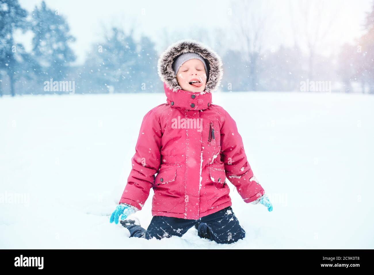 Cute adorable funny Caucasian excited girl child eating licking snow ...