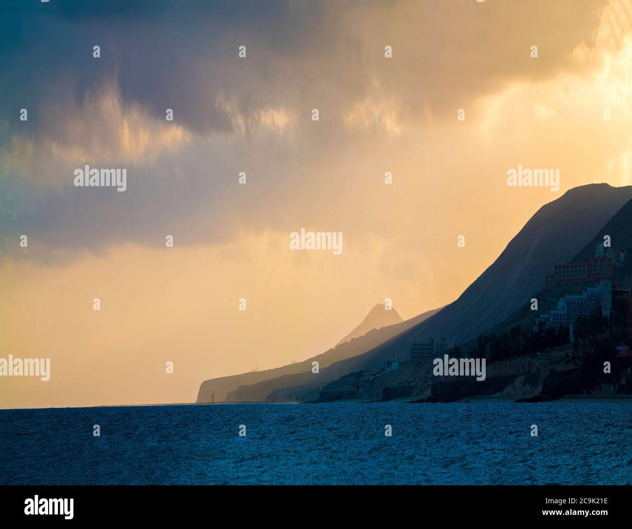 Sun setting behind mountains Stock Photo - Alamy