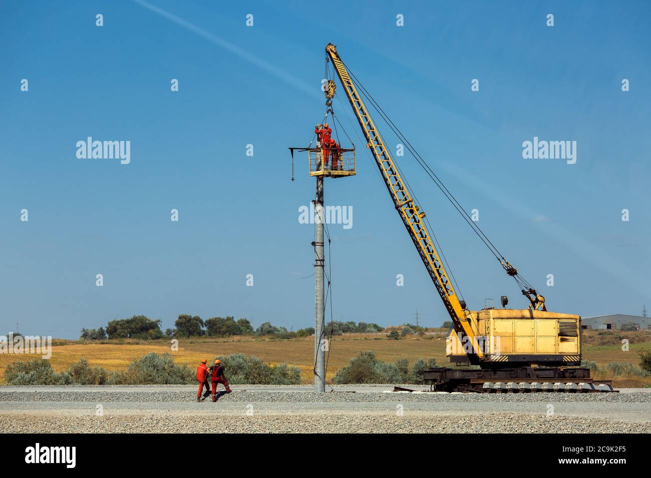 a railroad crane with a cradle lifted workers on the installation of ...