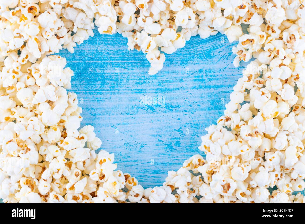 Pop corn in the shape of heart on blue background and with copy space ...