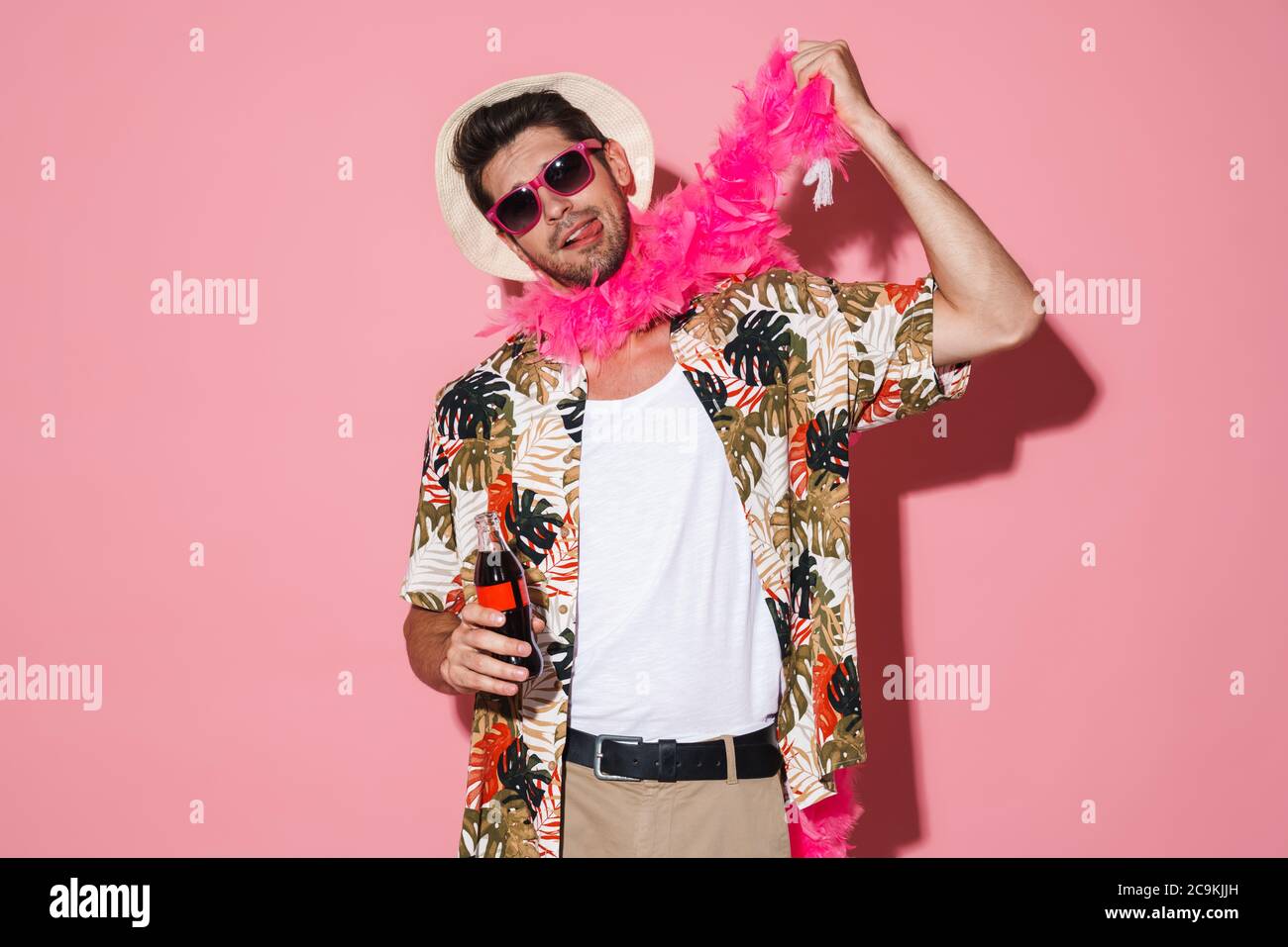 Portrait of cheerful young man making fun with boa while drinking soda ...