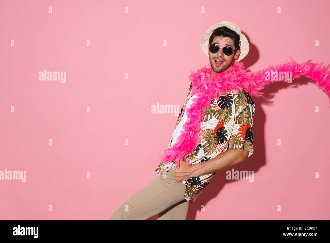 Portrait of cheerful young man wearing boa dancing and smiling isolated ...